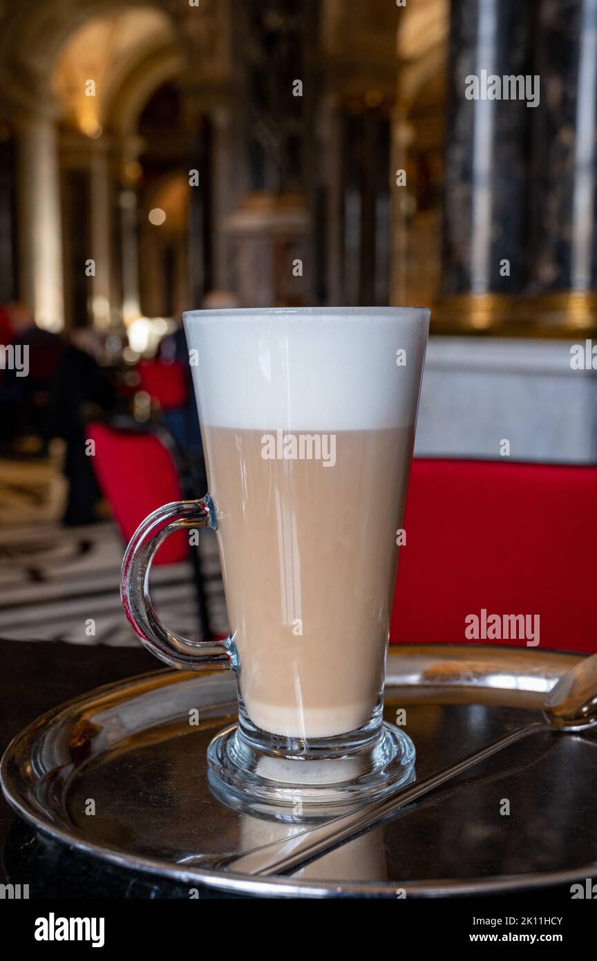 Glass cup of coffee latte served in classic old Austrian café ...