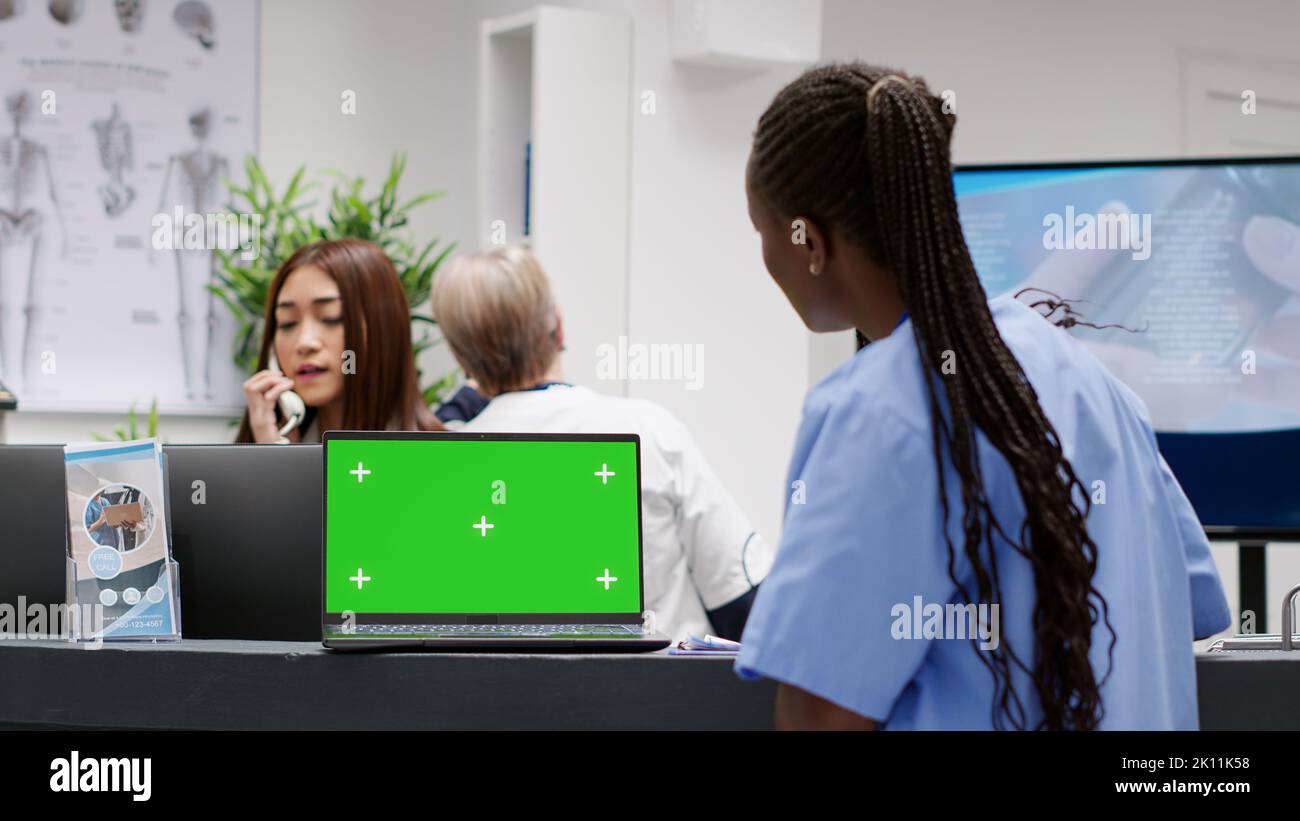African american nurse using laptop with greenscreen display at ...