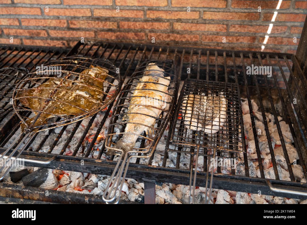 Fresh fish grilling on old charcoal parrillas white fish sea bass and ...