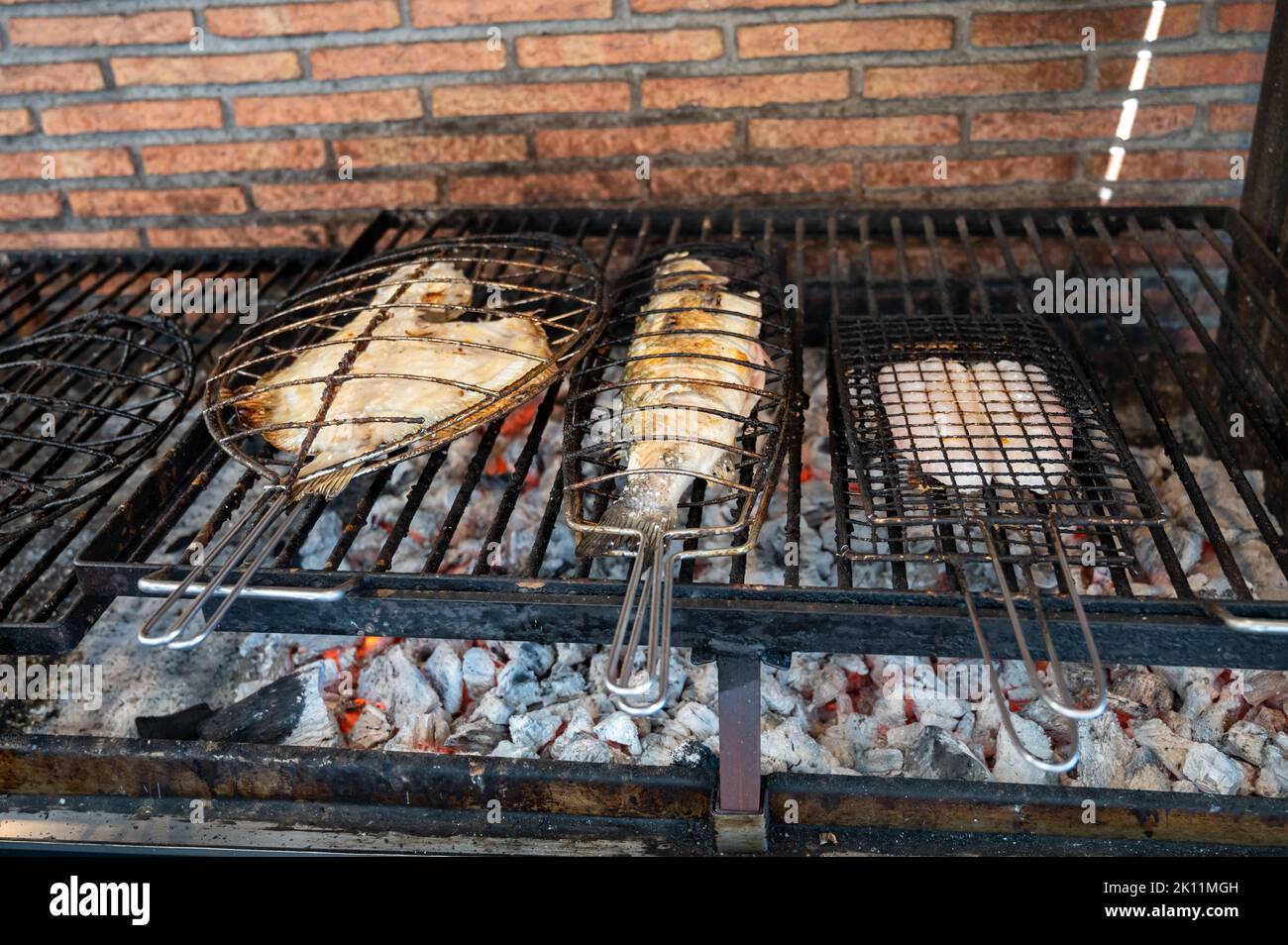 Fresh fish grilling on old charcoal parrillas white fish sea bass and ...