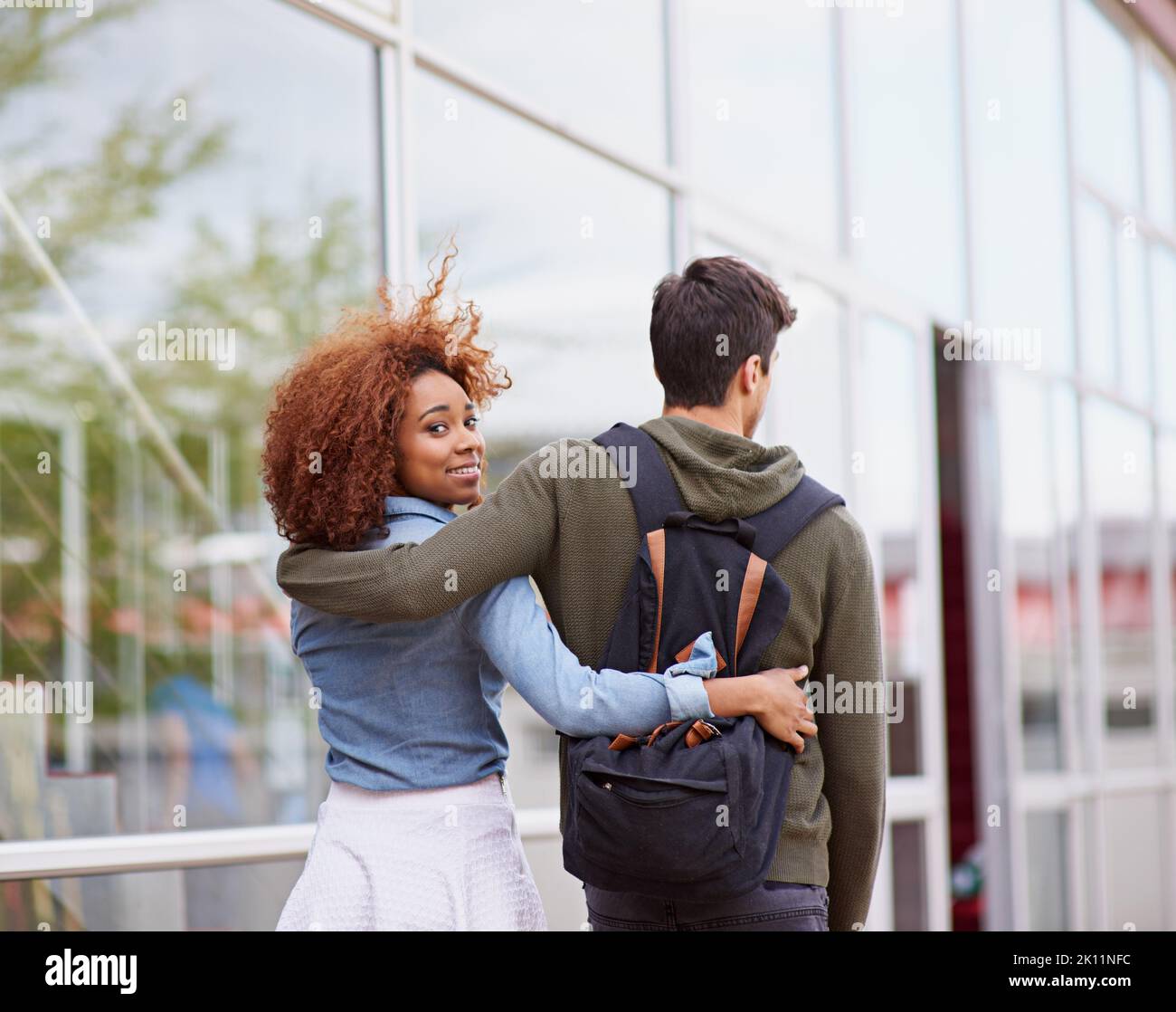 Shes looking over his shoulder. a young couple on campus Stock Photo ...