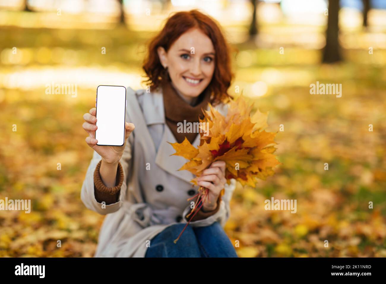 Glad caucasian millennial red-haired woman in raincoat with yellow ...