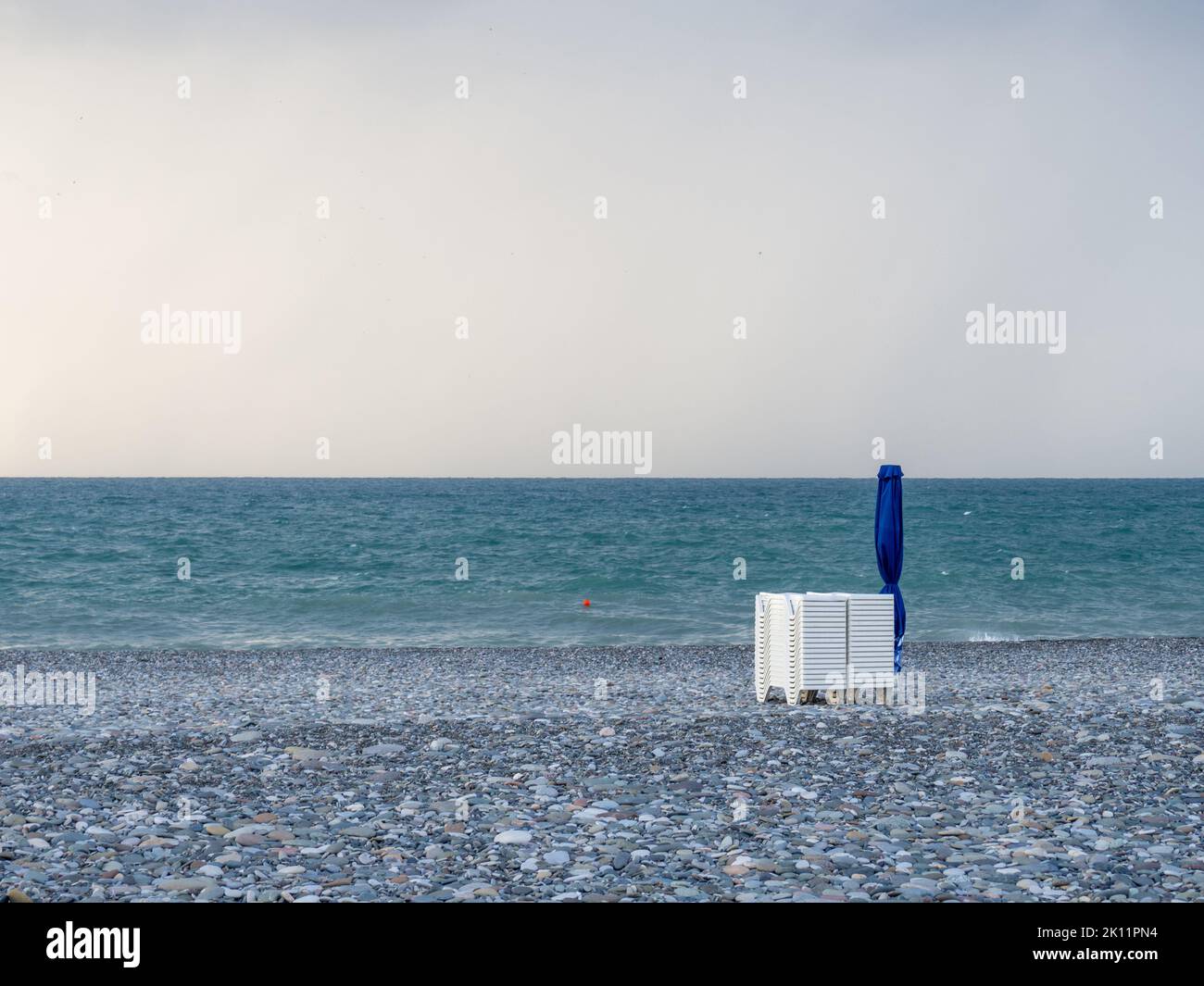 Folded beach umbrella and sunbeds. End of beach season. Not bathing ...