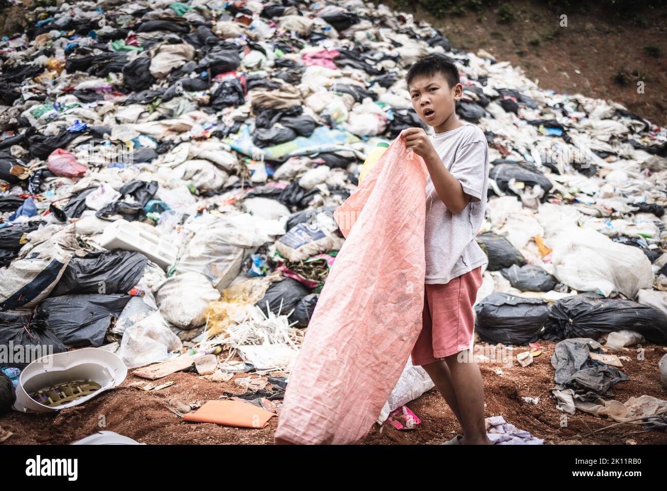 A poor boy collecting garbage waste from a landfill site in the ...