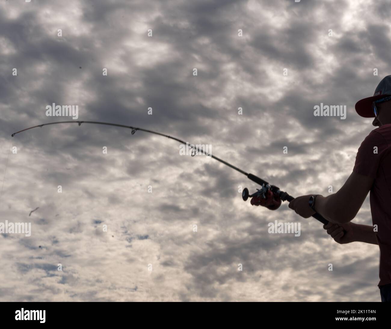 Fishing rod wheel closeup, man fishing with a beautiful sunrise behind ...