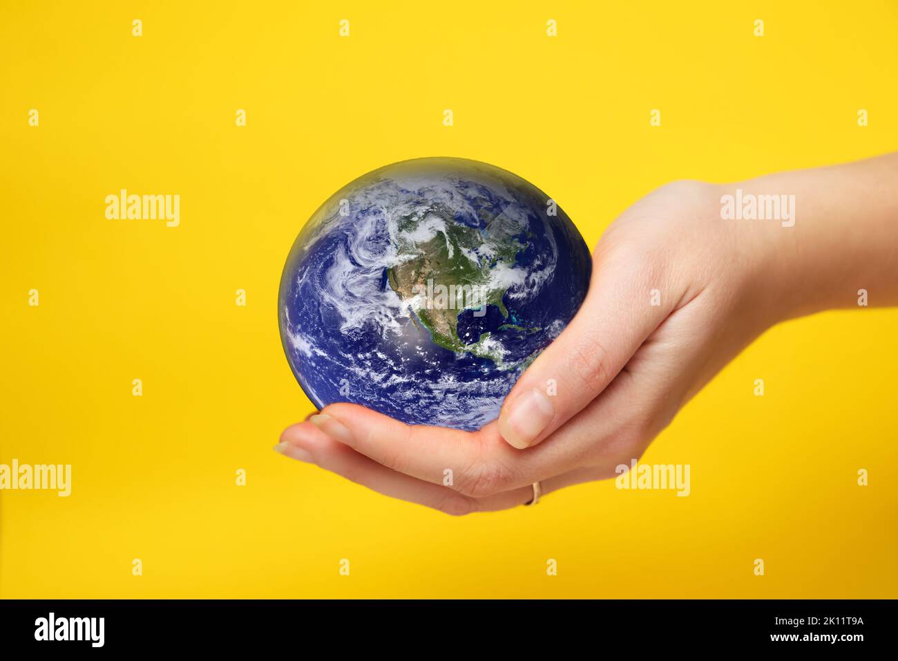 Defocus female hand holding planet globe on yellow background ...