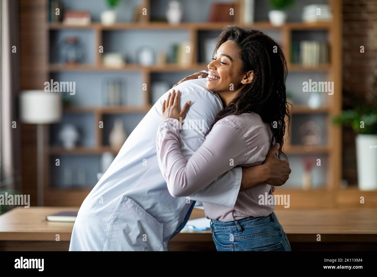 Doctor hugging cheerful black lady patient, clinic interior Stock Photo ...