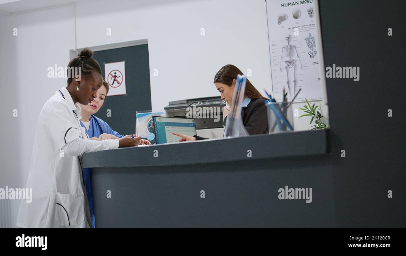 Diverse medical staff using checkup reports to help with appointments ...