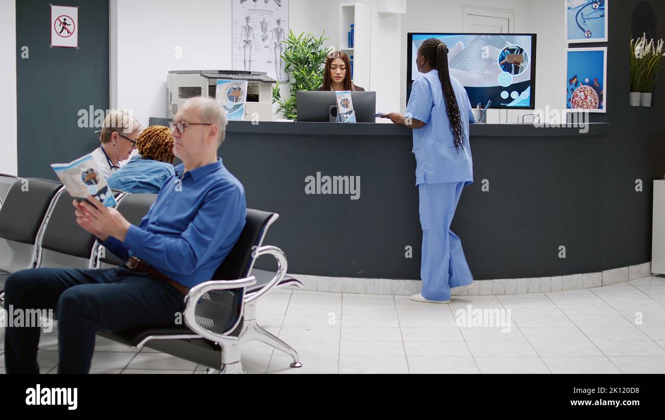 African american nurse talking to asian receptionist at hospital ...