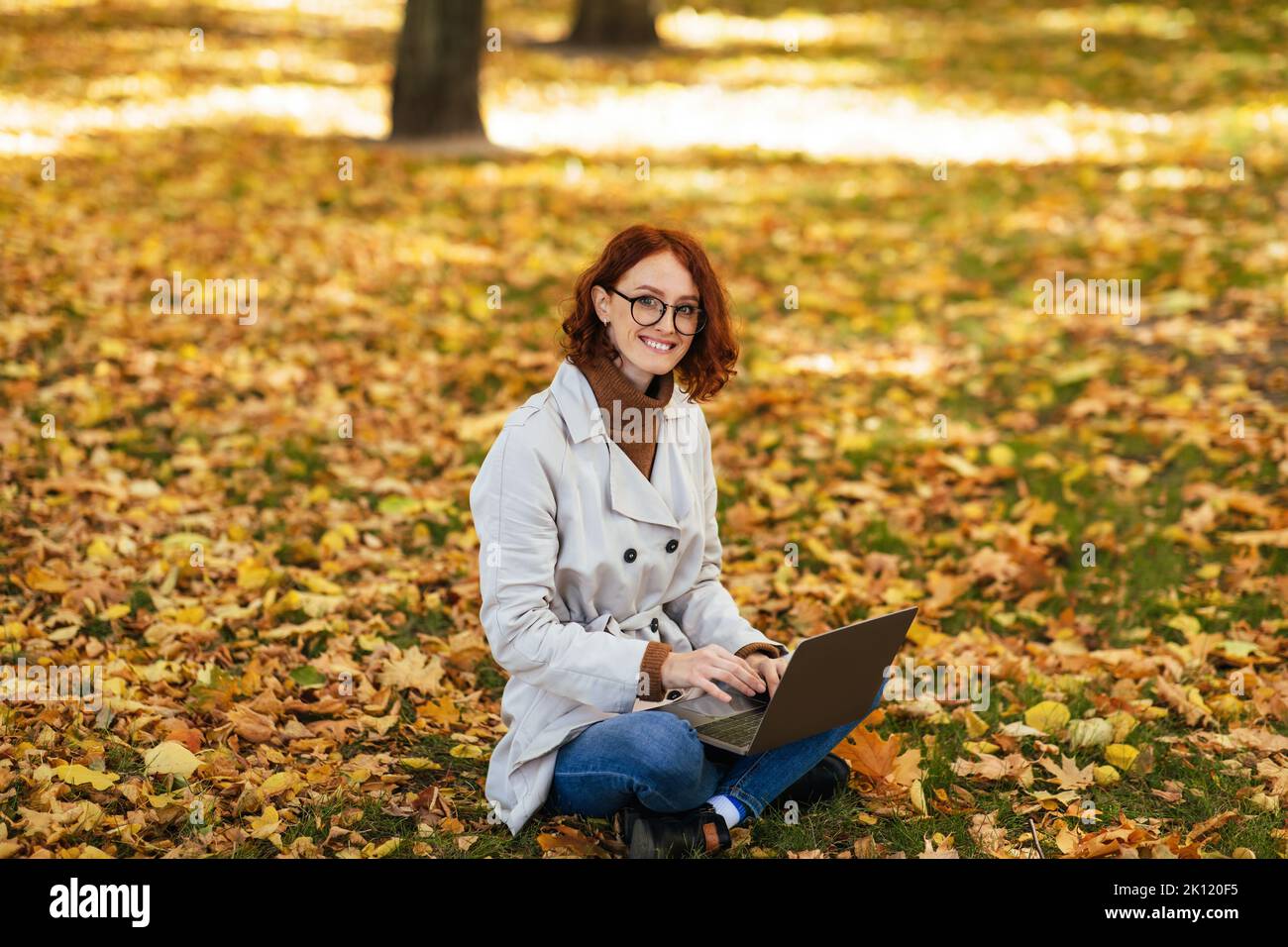 Cheerful caucasian millennial red-haired lady in raincoat and glasses ...