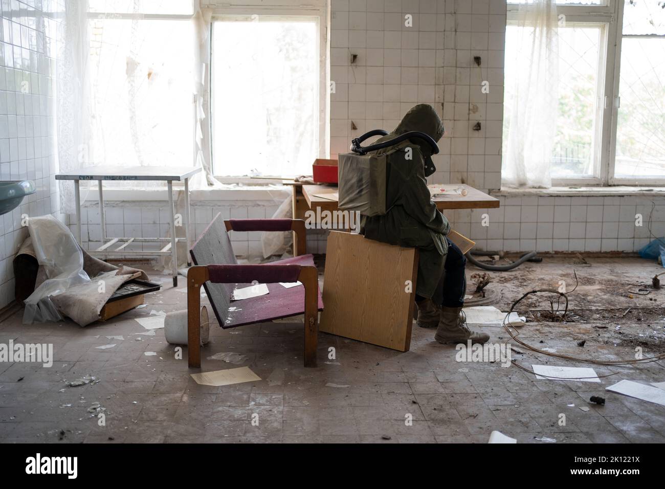 Post apocalyptic survivor in gas mask sitting in a ruined building ...