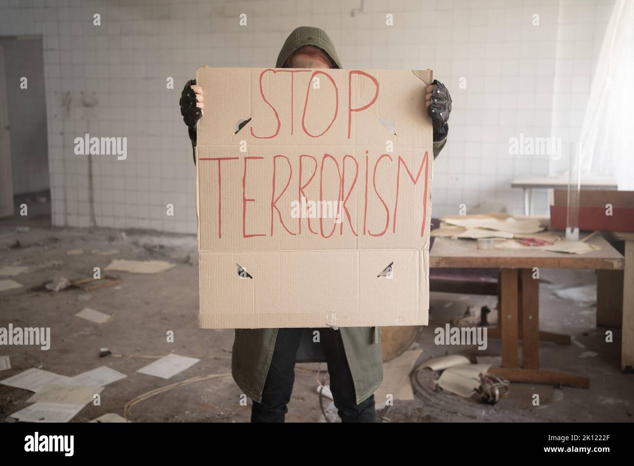 Stop Terrorism card in female hands, who standing in abandoned building ...