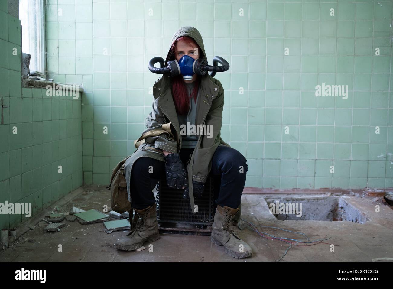 Post apocalyptic survivor in gas mask sitting in a ruined building ...