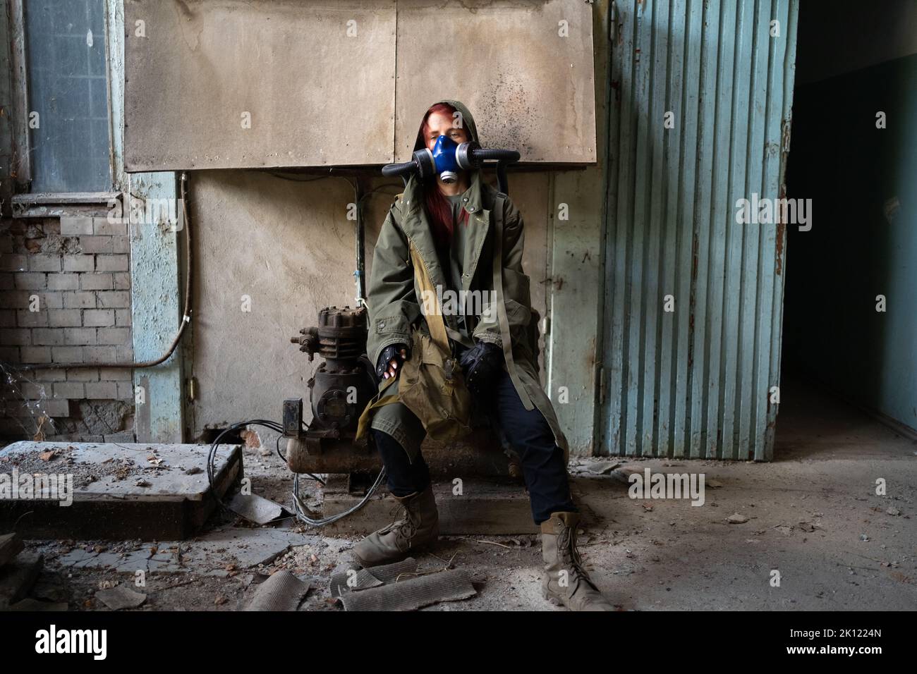 Post apocalyptic female survivor in gas mask sitting in a ruined ...