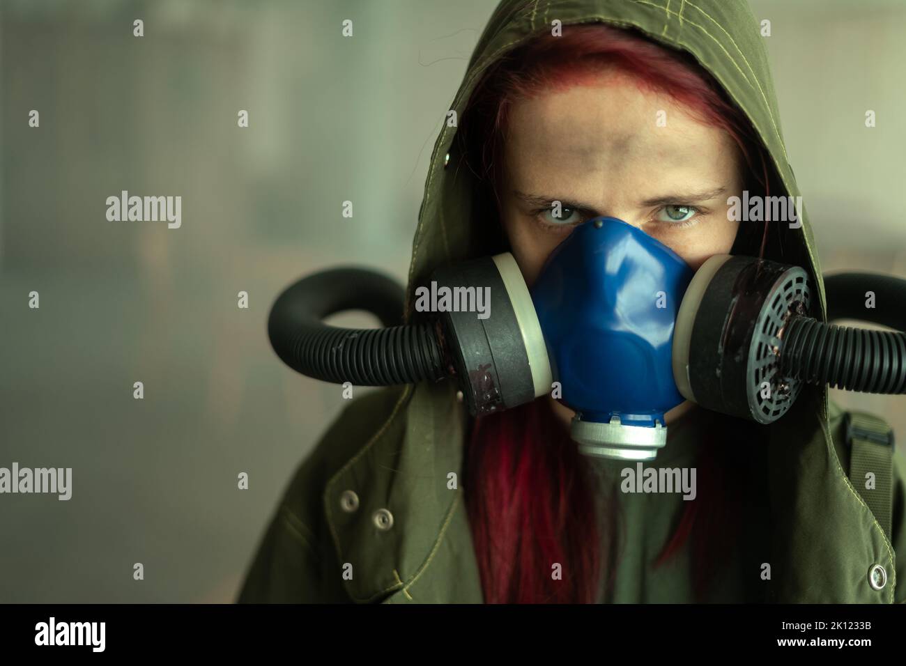 Young pandemic survivalist woman in gas mask looking in front of her on ...