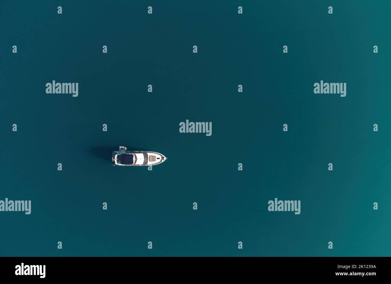 Aerial yacht on calm sea. Luxury cruise trip. View from above of white boat on deep blue water ...