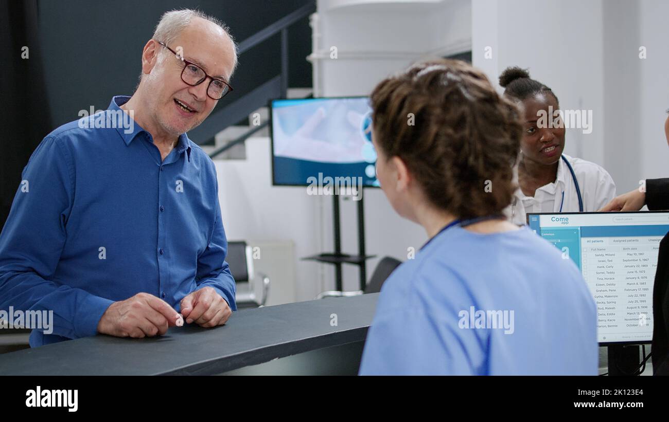 Medical assistant helping senior patient with appointment and reception ...