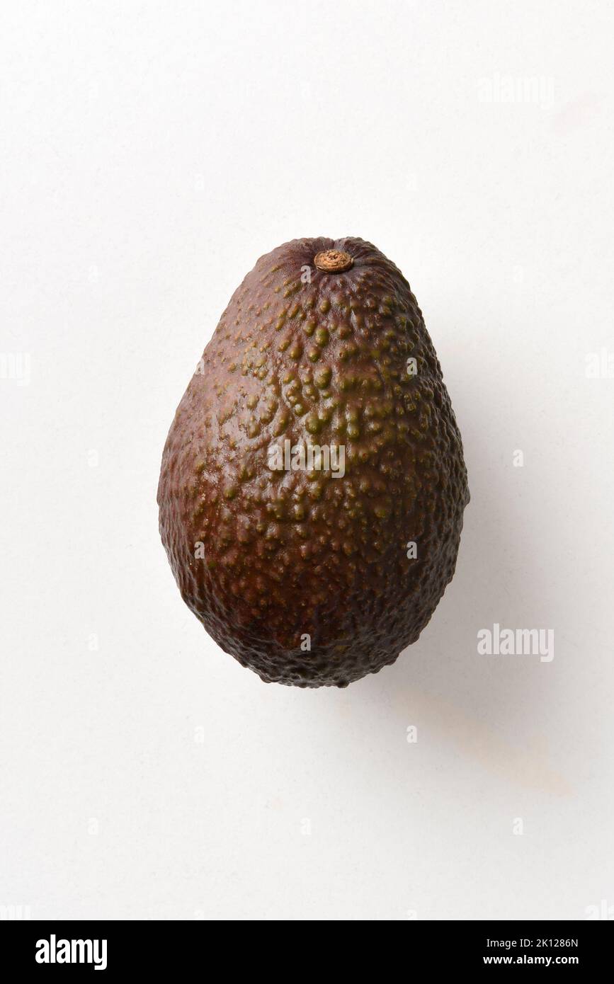 Detail of whole ripe avocado with skin texture isolated on white table ...
