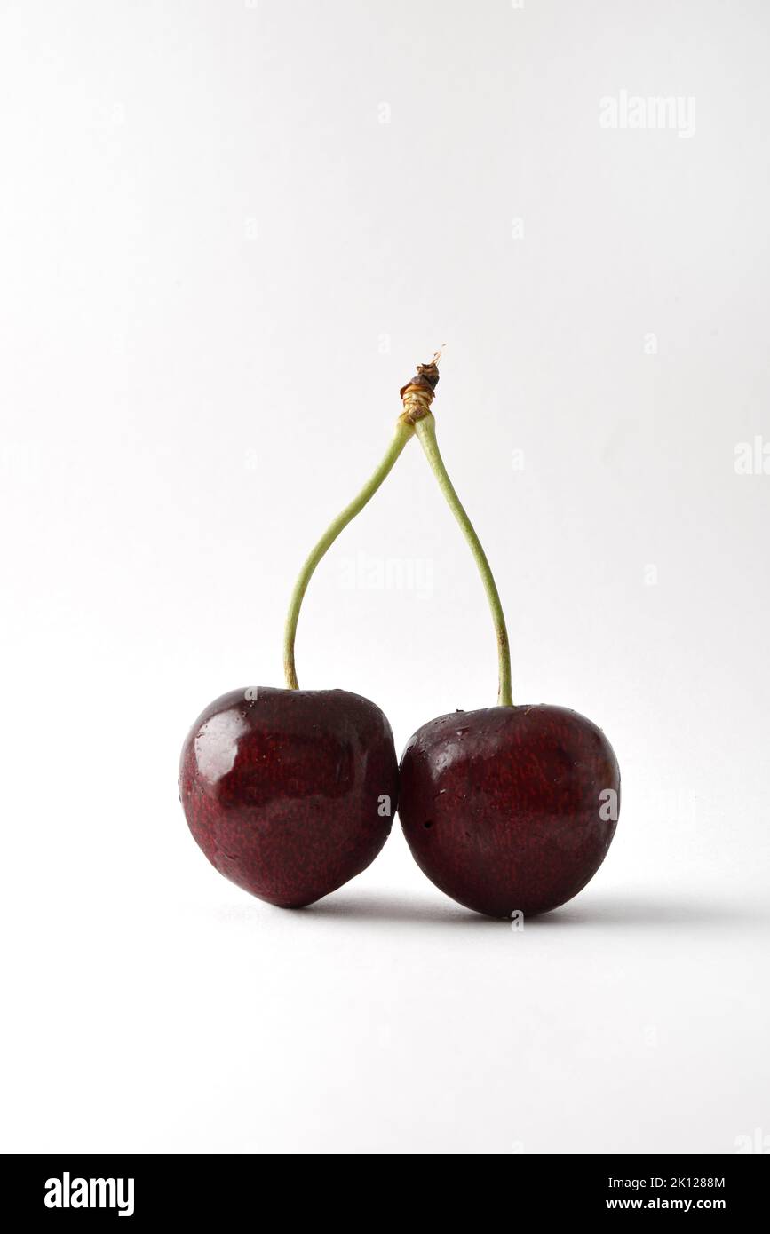 Detail of two joined cherries on white table with white isolated ...
