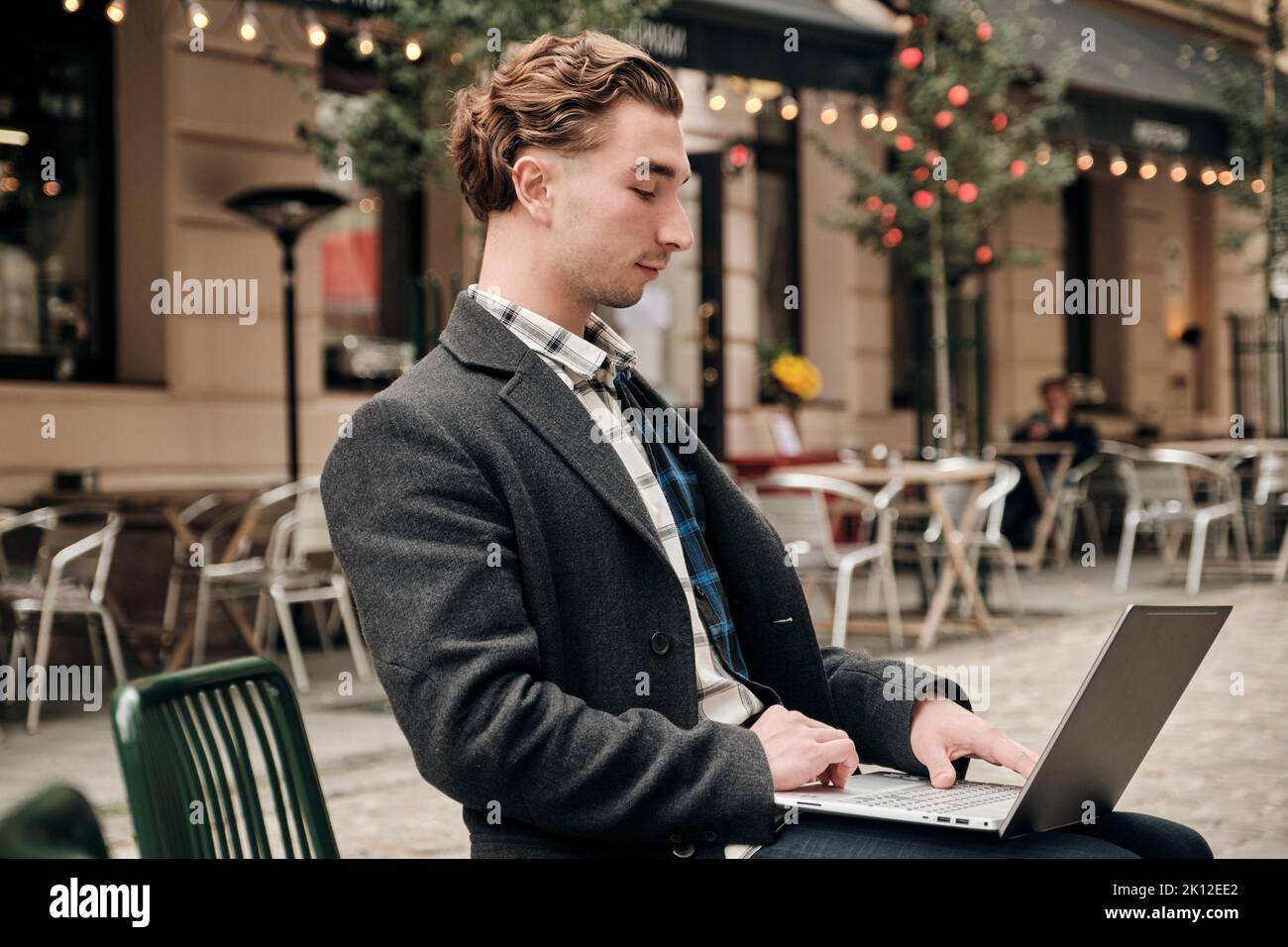 Handsome elegant man working outside at a cafe, focused on his laptop ...