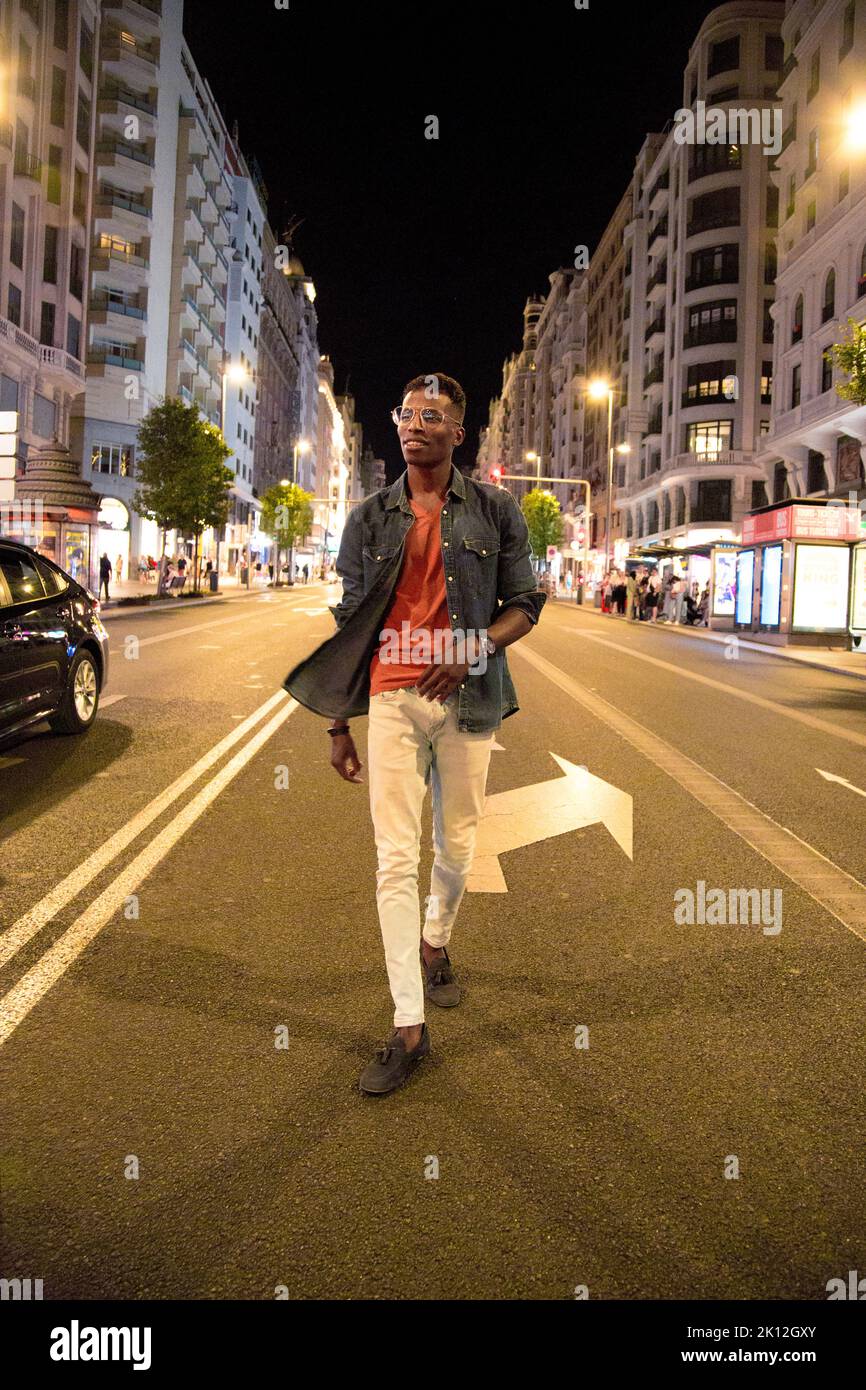 Vertical portrait of an african man walking in the middle of the road ...