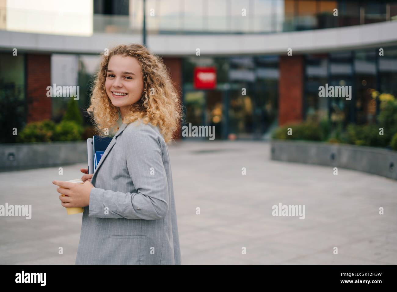 Portrait of successful student holding textbooks smiling turning her ...