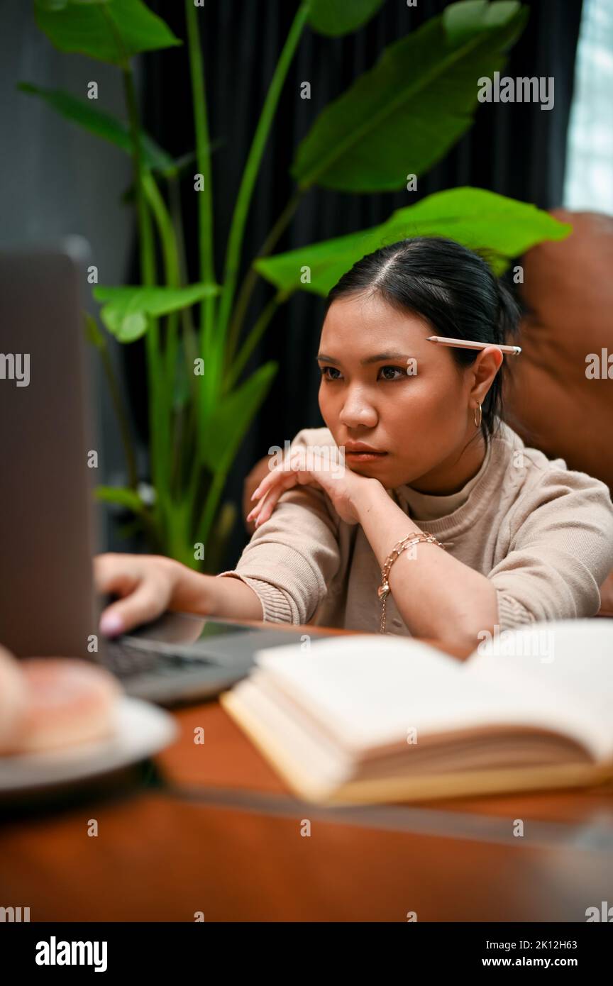 Portrait, A concentrated and serious young Asian female college student doing her project ...