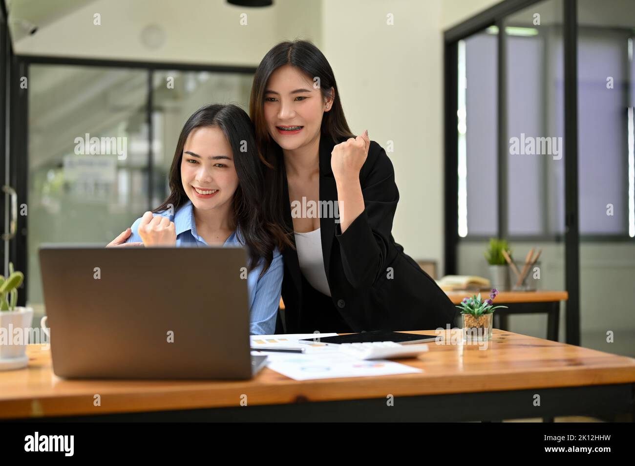 Attractive and cheerful young Asian businesswomen at the office desk ...