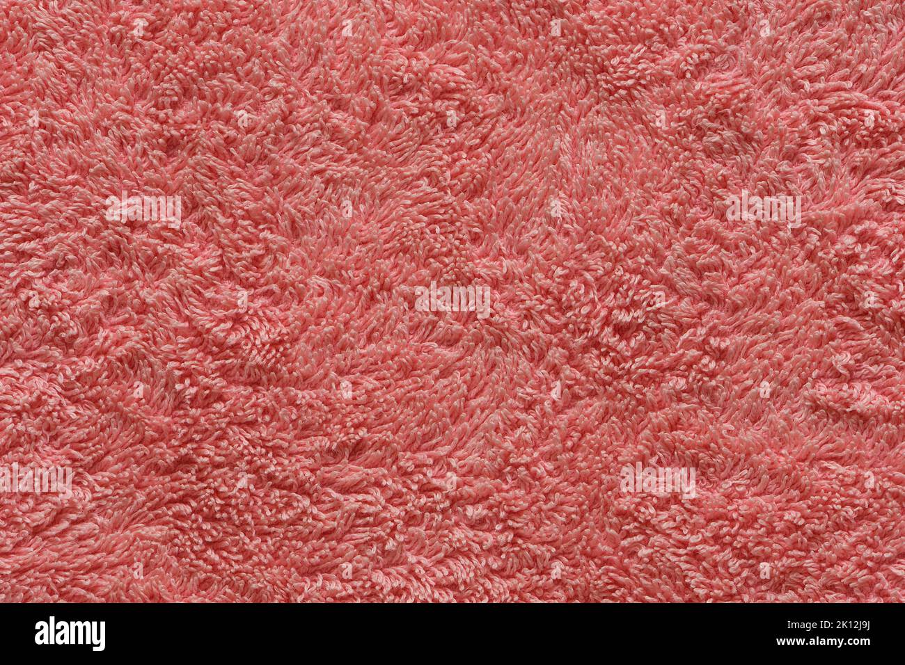 An extreme close-up of a salmon coloured fluffy, shaggy, bathroom towel ...