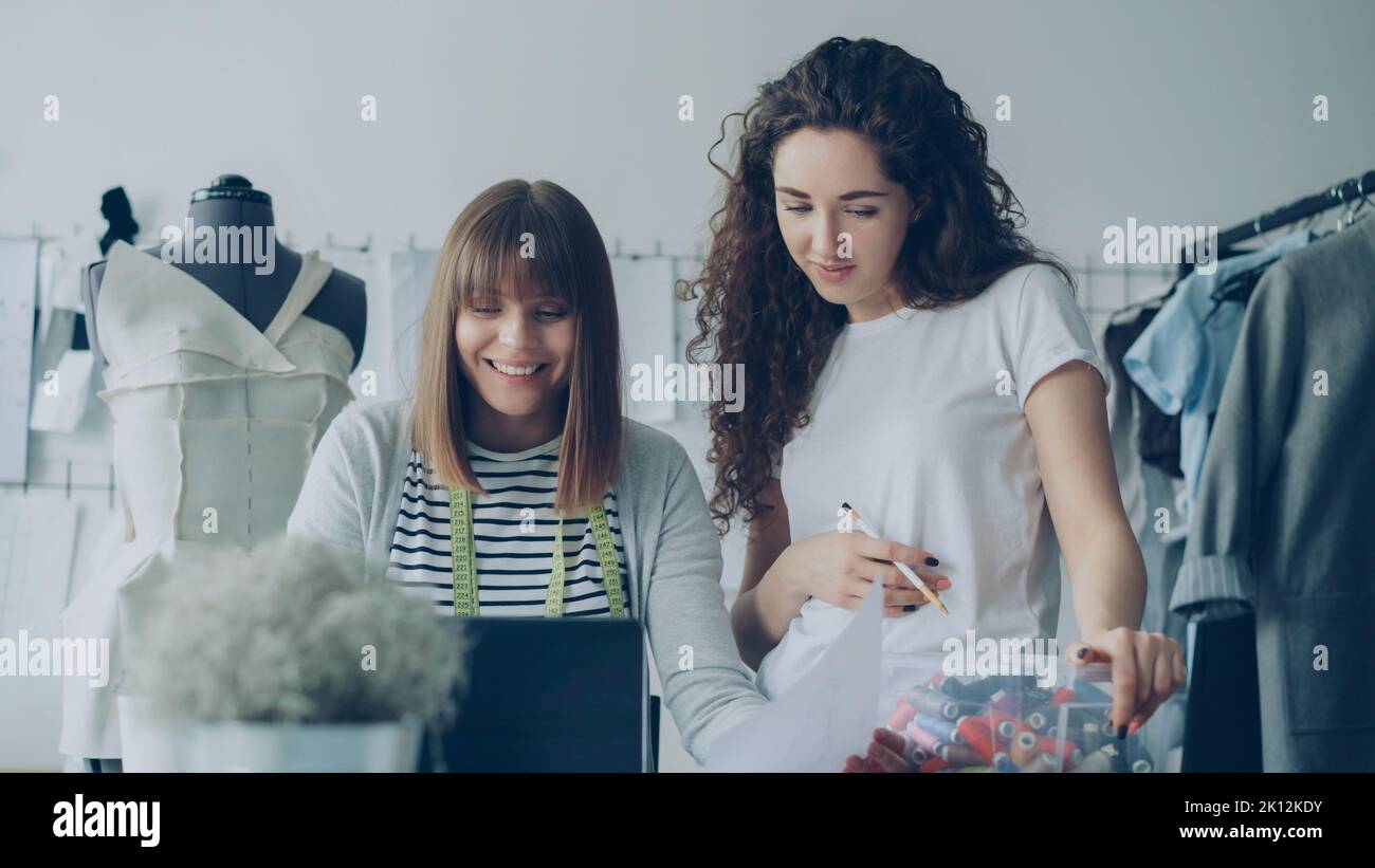 Cheerful creative clothing designers are watching laptop screen, having ...