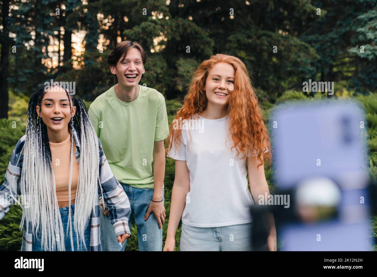 A group of people using a tripod and phone laughing while shooting ...