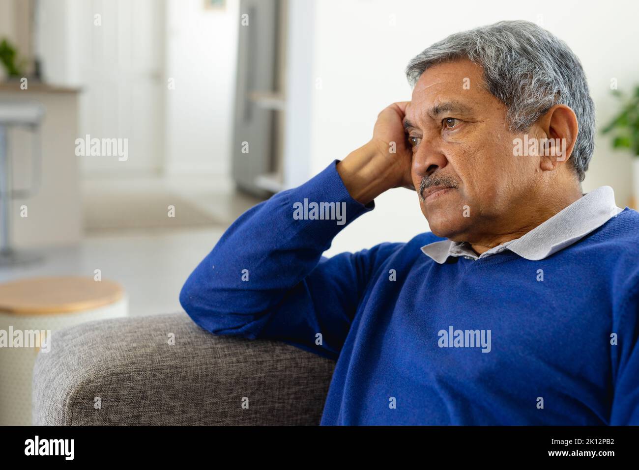Tired, depressed senior biracial man sitting on couch in living room ...