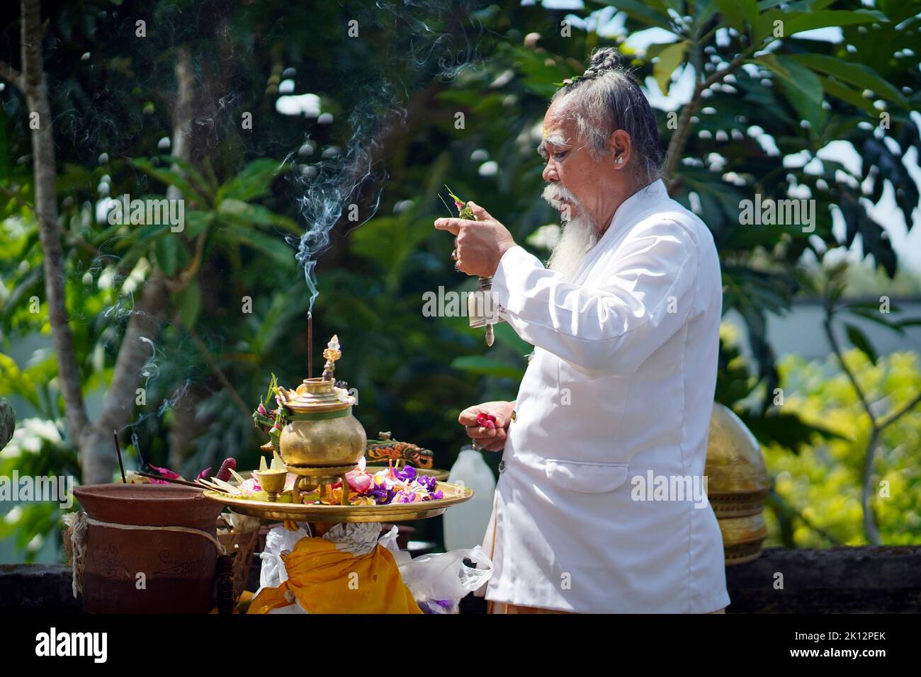 Bali, Indonesia - April 13, 2022 - A Hindu priest holding golden bell ...