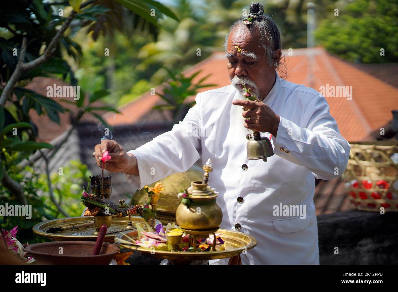 Bali, Indonesia - April 13, 2022 - A Hindu priest holding golden bell ...