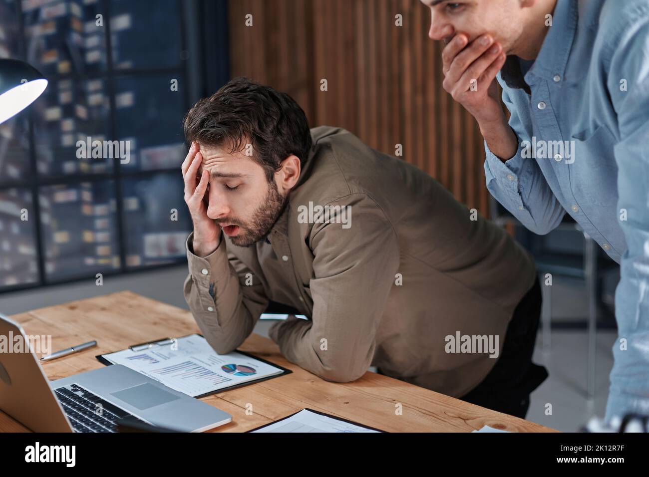 two tired employees working with financial documents until late at ...