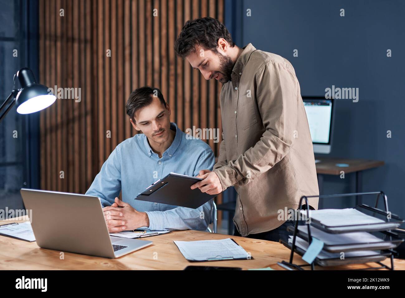 colleagues discussing a business document late at night in the office ...