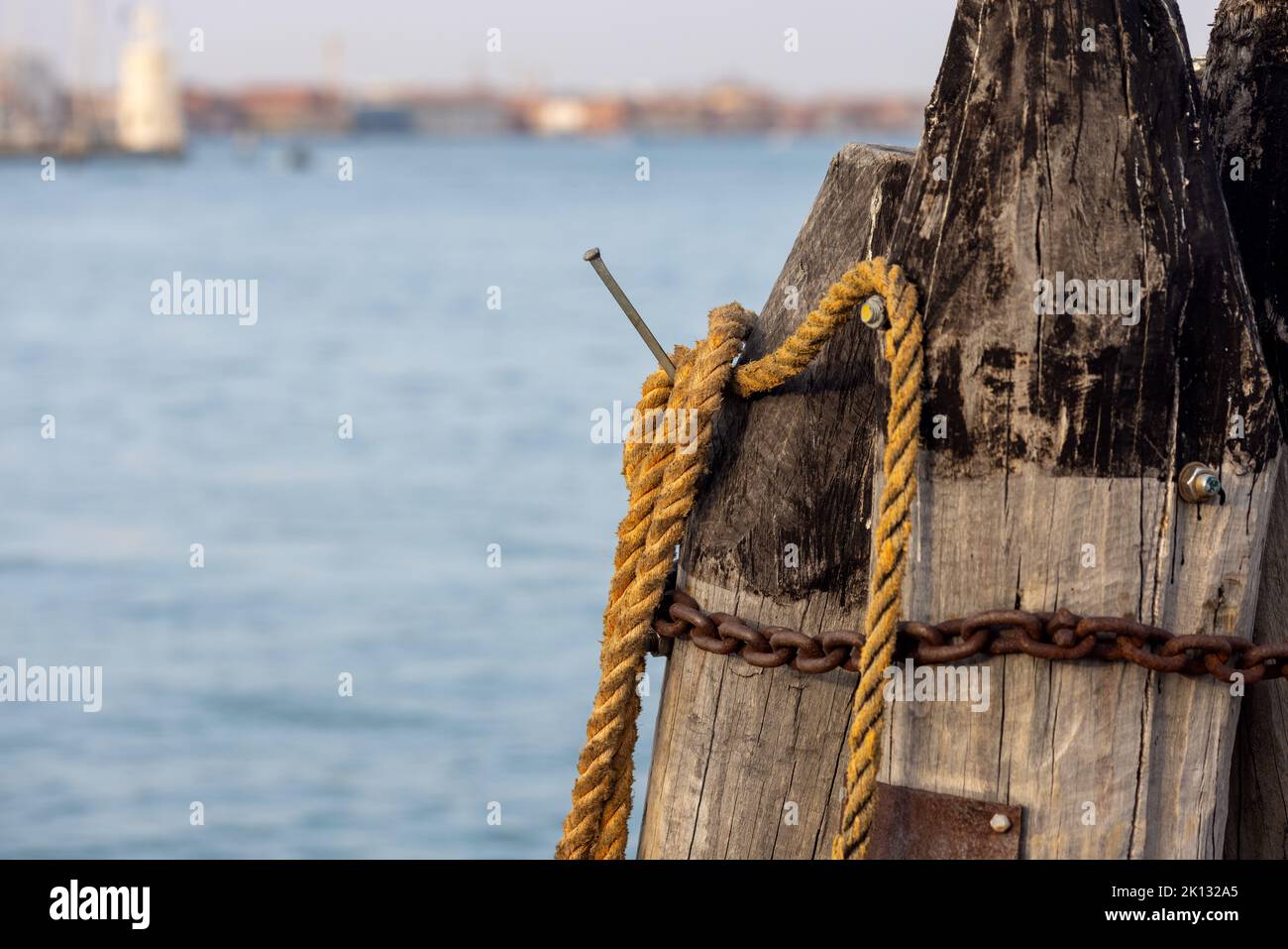 Wooden pillars with old rope and chain in sea at Venice dock. Large ...