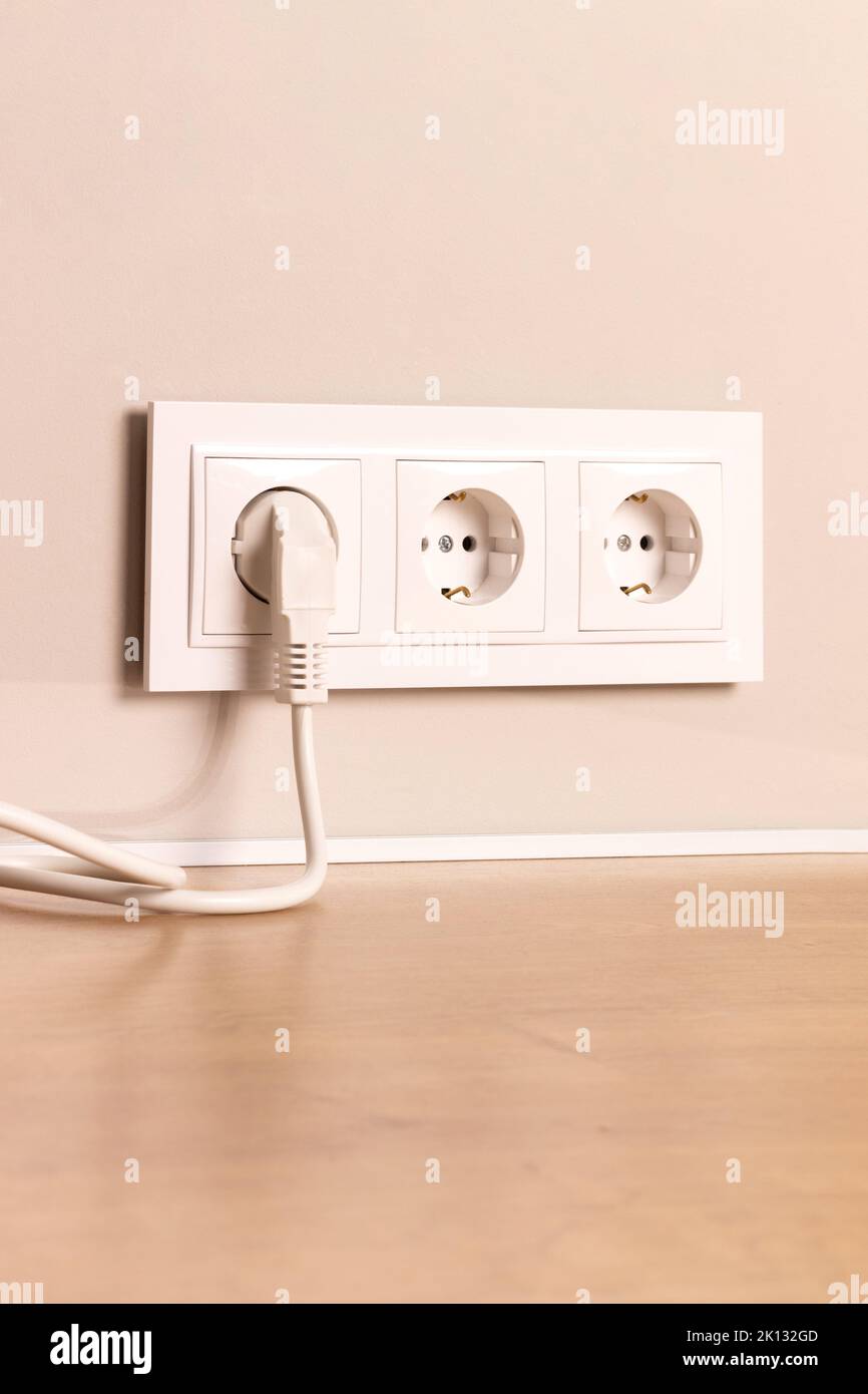 Group of white european electrical outlets with plug inserted into it ...