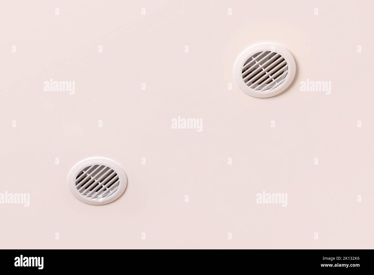 Round air vents with white plastic grate on beige ceiling Stock Photo ...