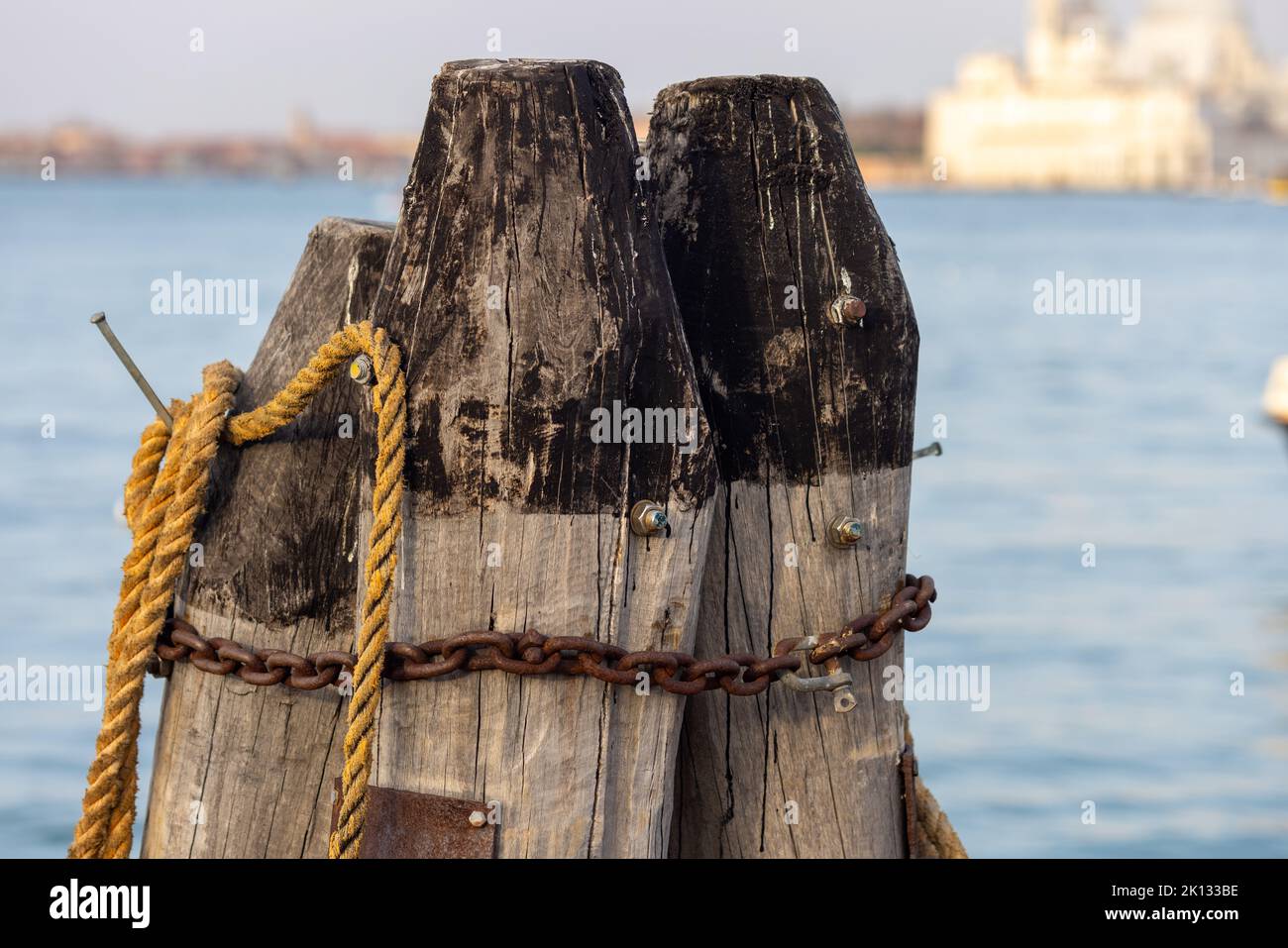 Wooden pillars with old rope and chain in sea at Venice dock. Large ...