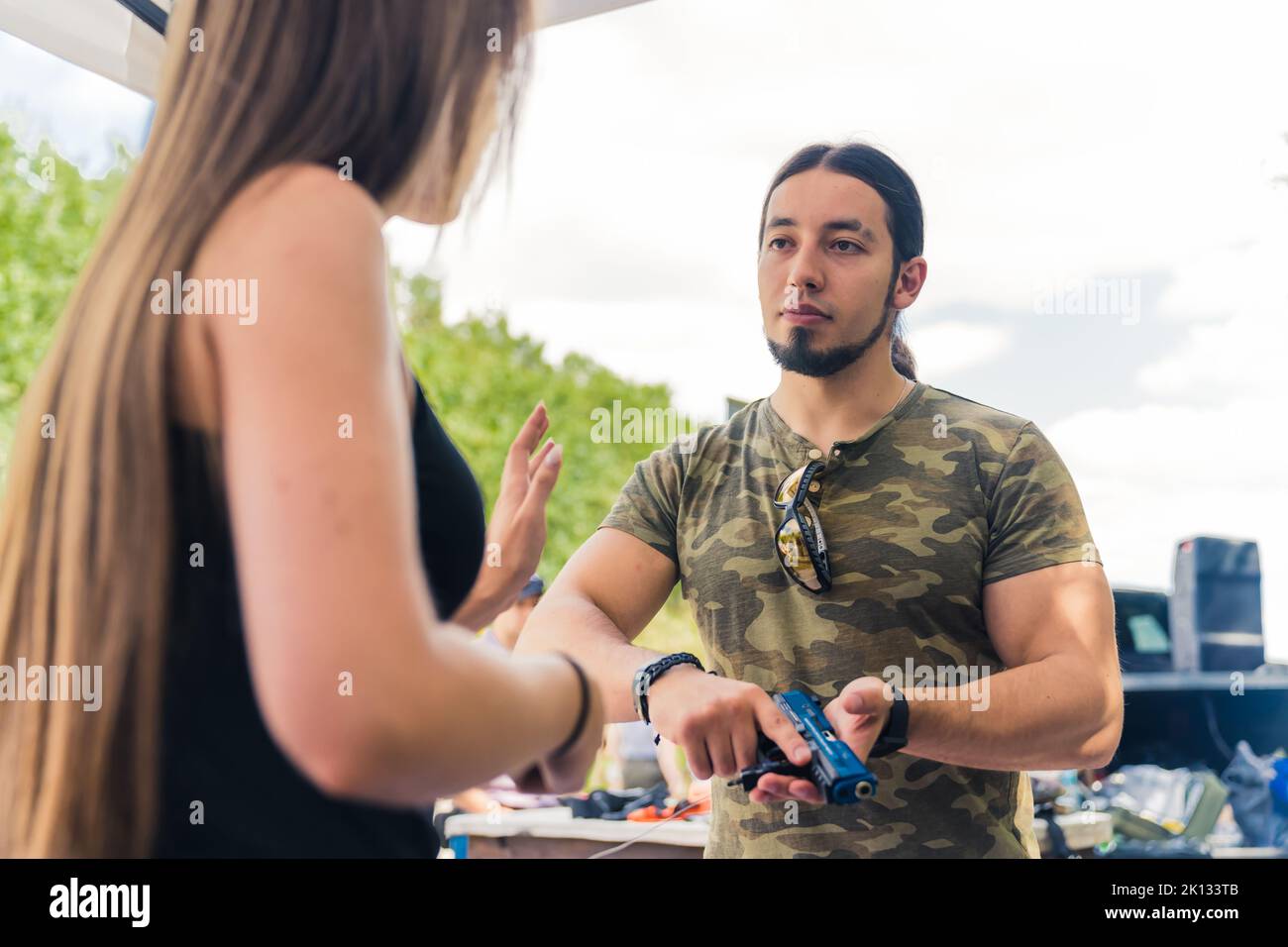 male instructor with black hair and a beard teaching a young woman how ...