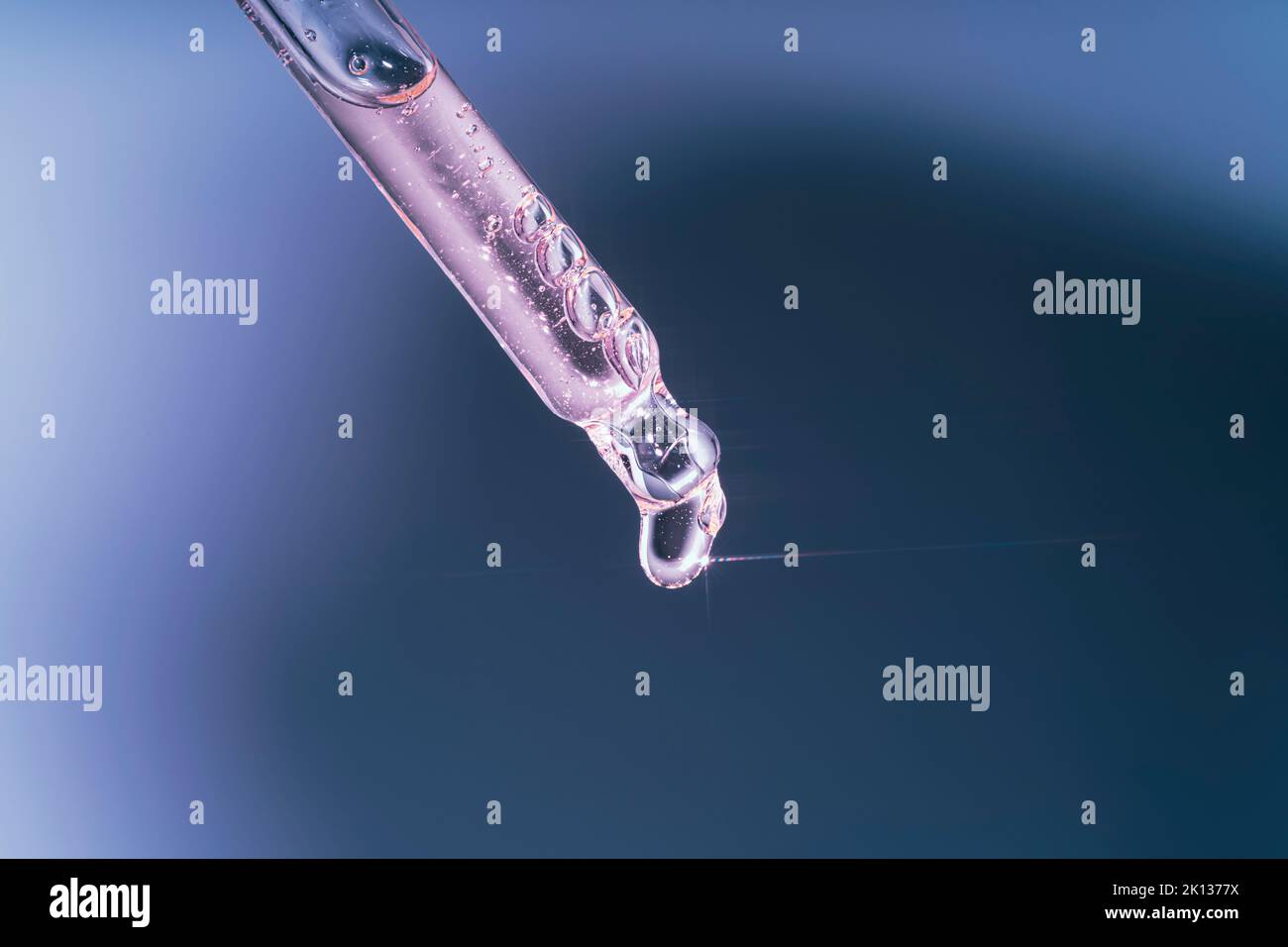 Liquid serum and dropper on a blue background top view. Serum drops in ...