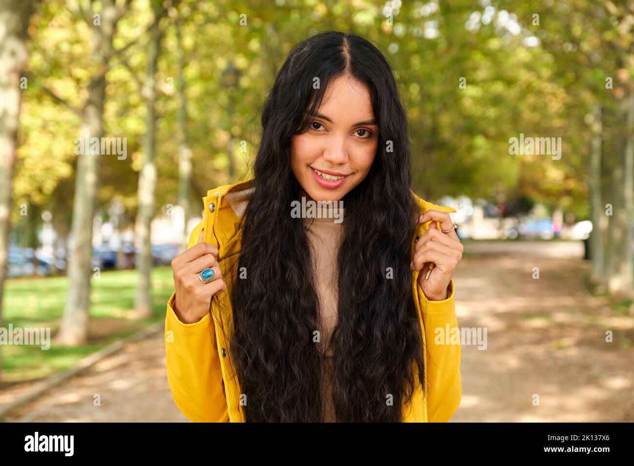 Young latin girl dressed in yellow raincoat posing looking at camera ...