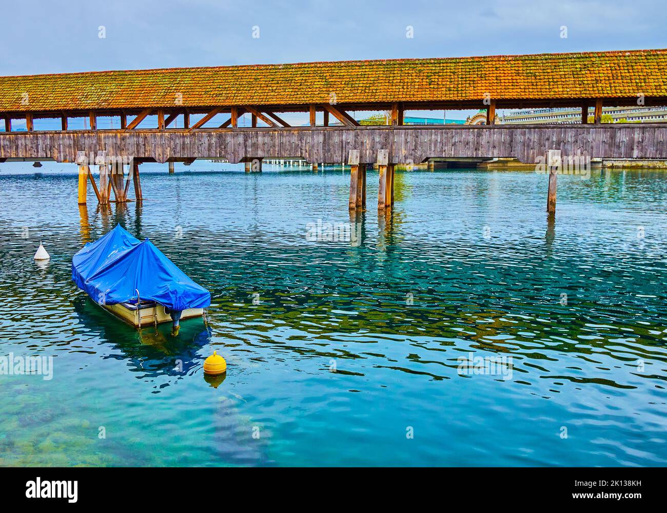 The covered boat in Reuss river and Kapellbrucke bridge on background ...
