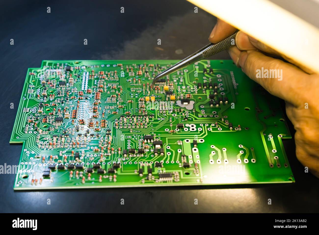 PCB printed circuit board with electrical components and hand with ...