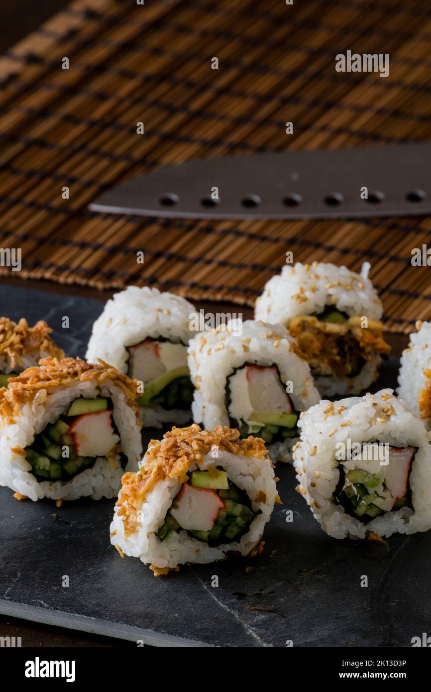 A vertical shot of a sushi set of Japanese seafood on the black stone ...