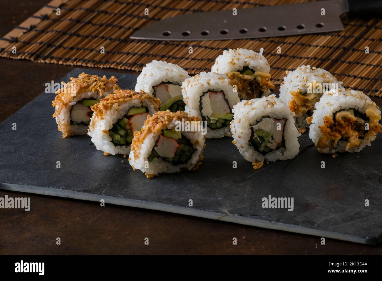 A sushi set of Japanese seafood on the black stone with a sharp knife ...