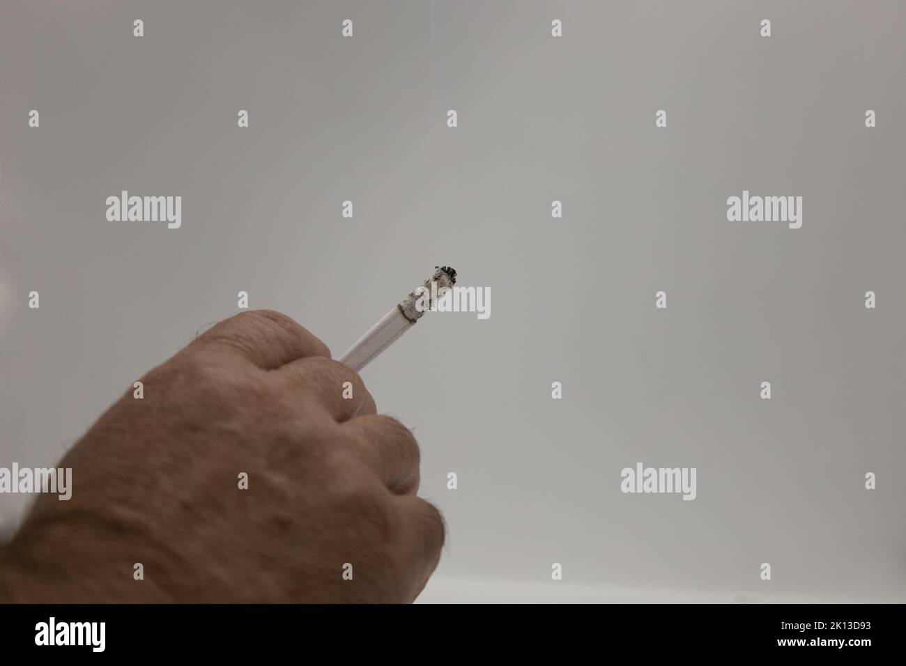 Cigarette in hand isolated on white background. Old man holding ...