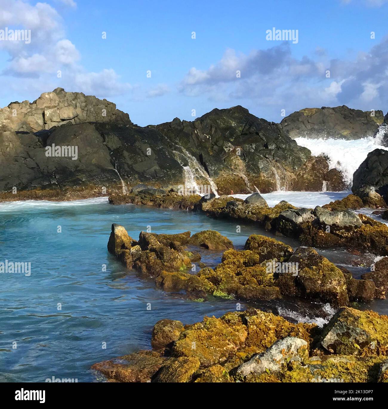 A scenic shot of a natural pool in the Caribbean Sea with waterfalls ...