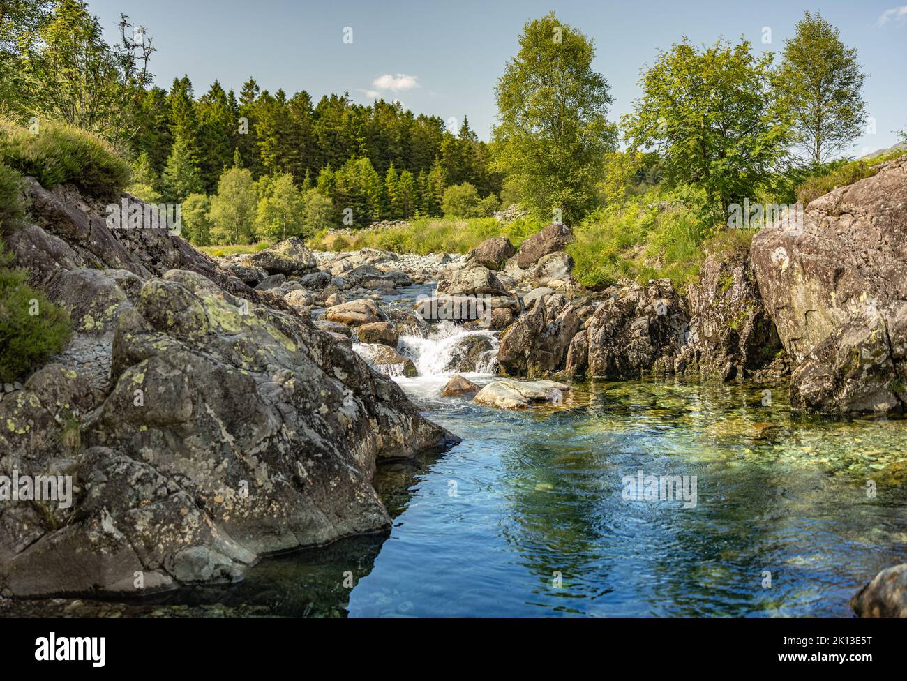 A River flowing between rocky cliffs with green trees Stock Photo - Alamy